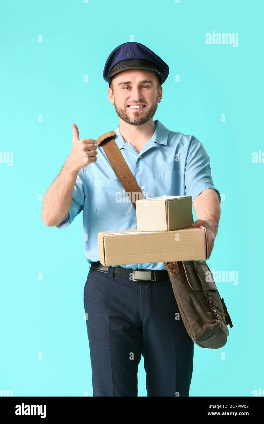 Handsome young postman on color background Stock Photo - Alamy