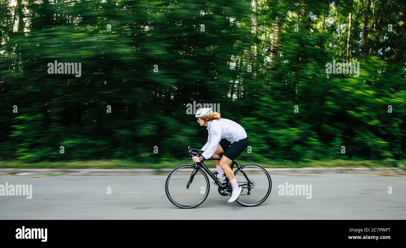 Side view of young athletic woman cycling on professional bike in a ...