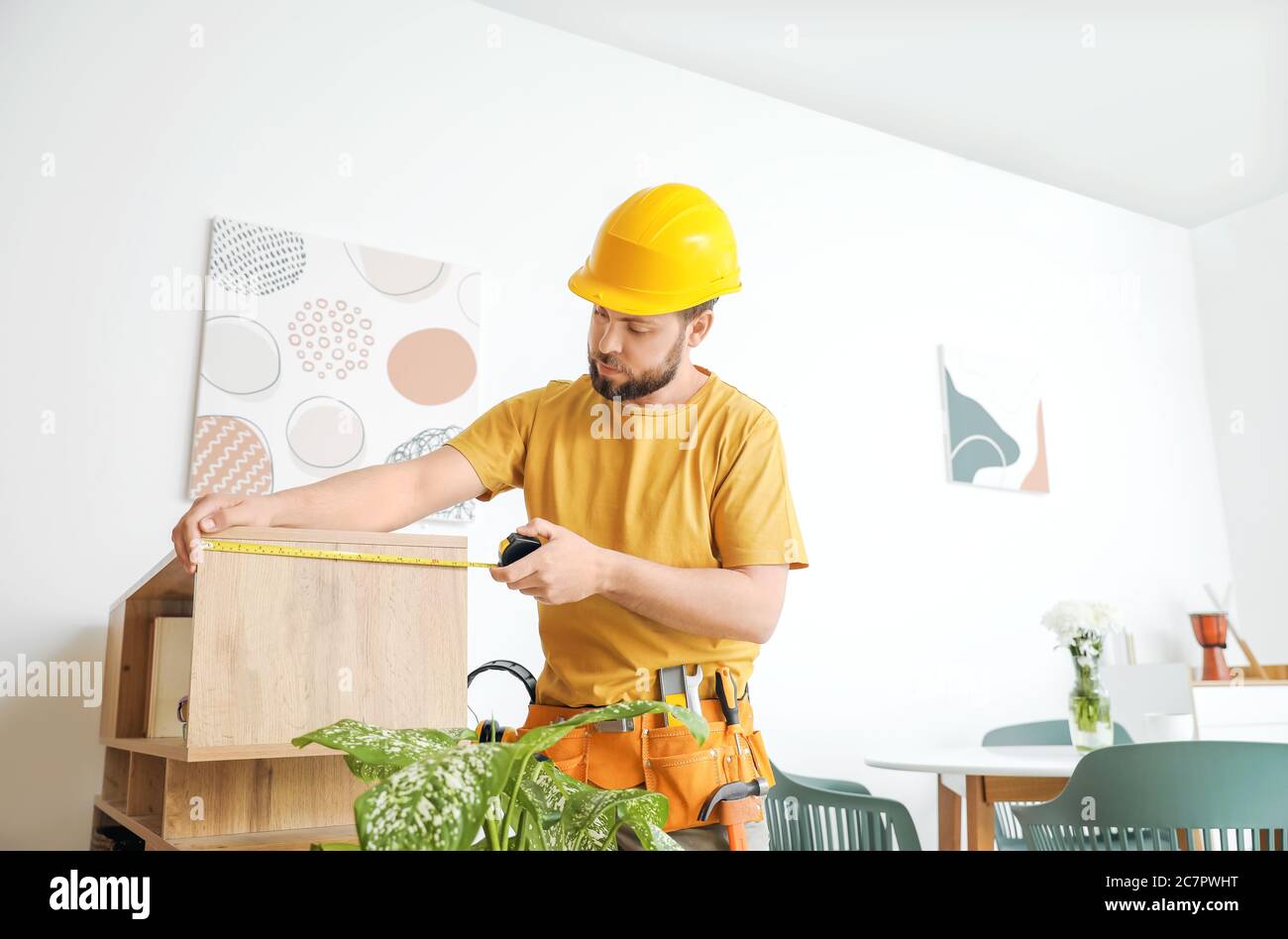 Male carpenter using tape measure in room Stock Photo - Alamy