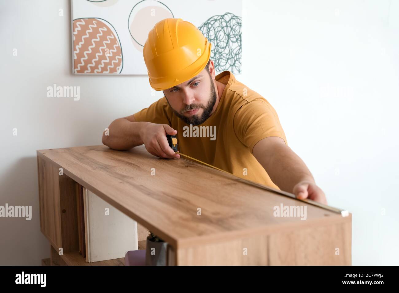 Male carpenter using tape measure in room Stock Photo - Alamy