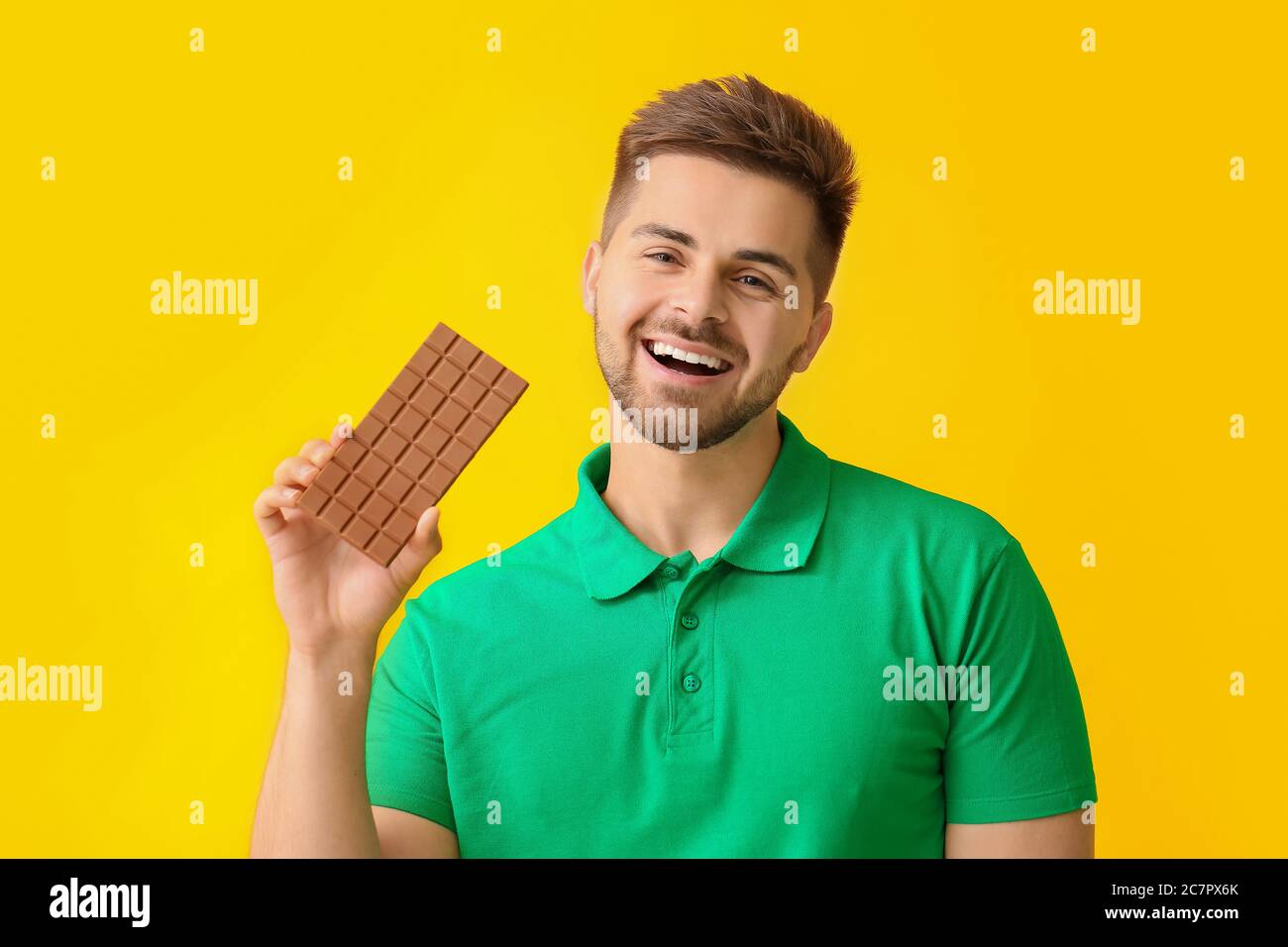 Handsome young man with tasty chocolate on color background Stock Photo ...