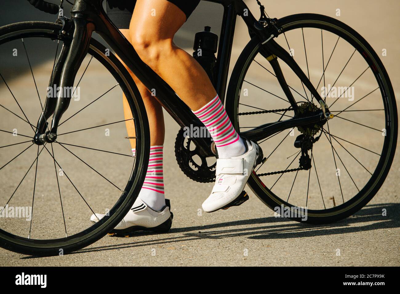Lower part of a female cyclist sitting on a pro slim bike. Cropped, no ...