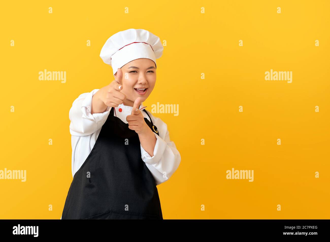 Beautiful Asian chef pointing at viewer on color background Stock Photo ...