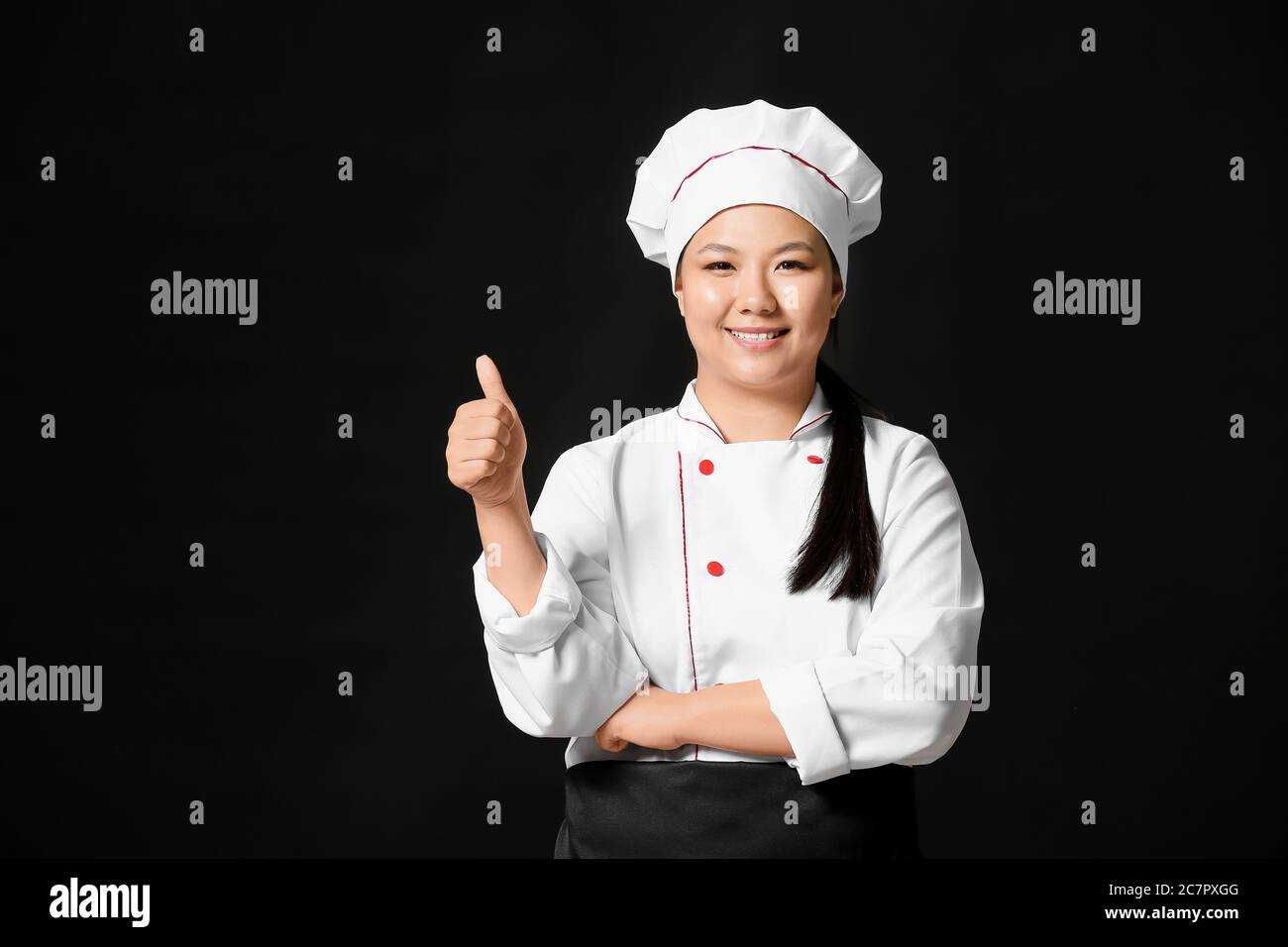 Beautiful Asian chef showing thumb-up gesture on dark background Stock ...