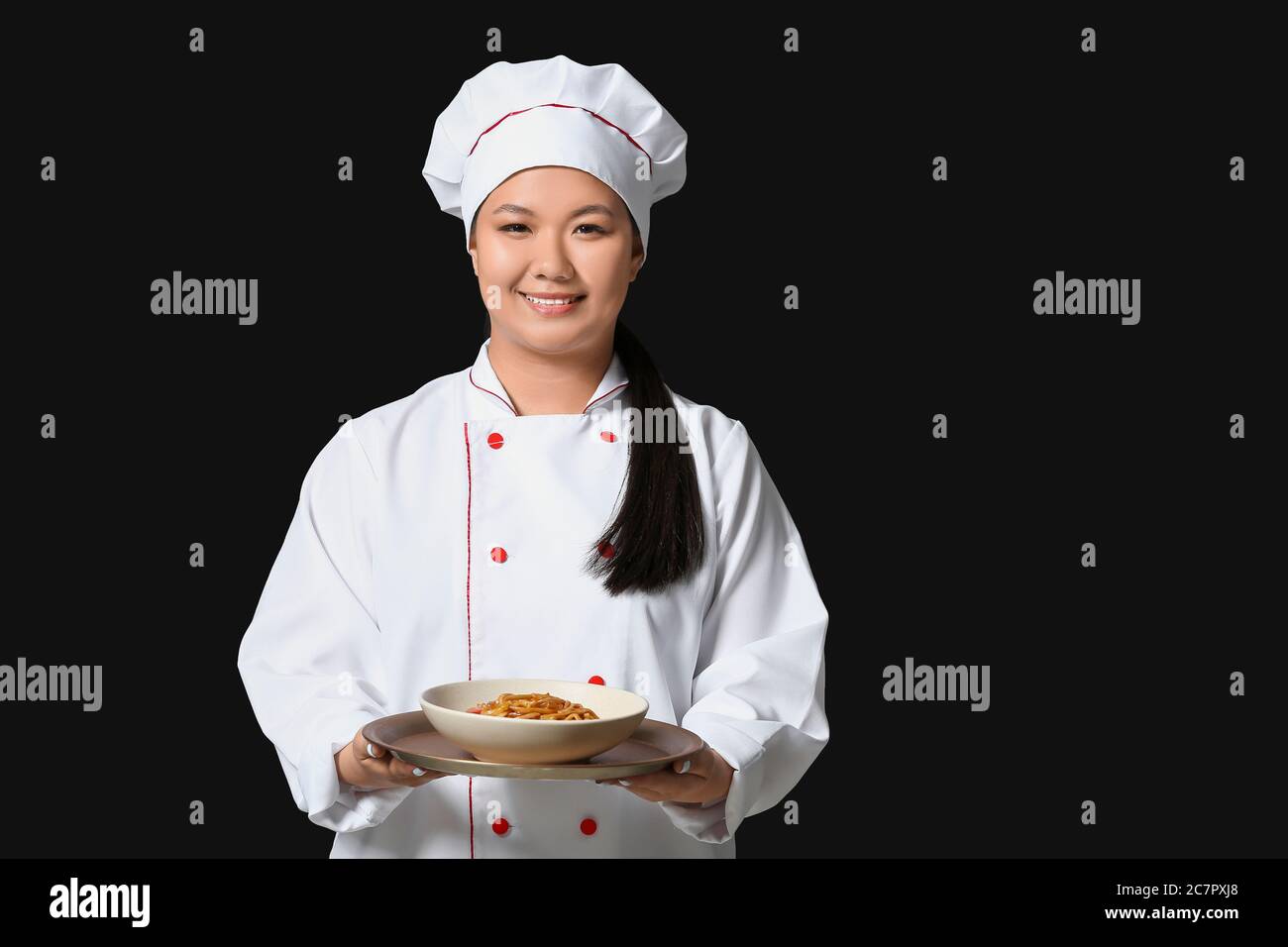 Beautiful Asian chef with dish on dark background Stock Photo - Alamy