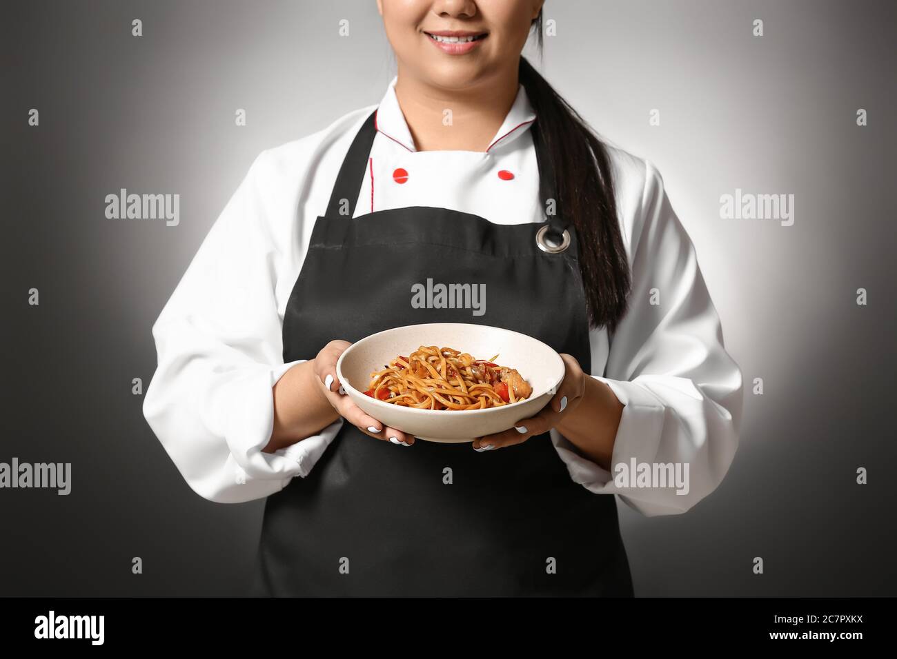 Beautiful Asian chef with dish on dark background Stock Photo - Alamy