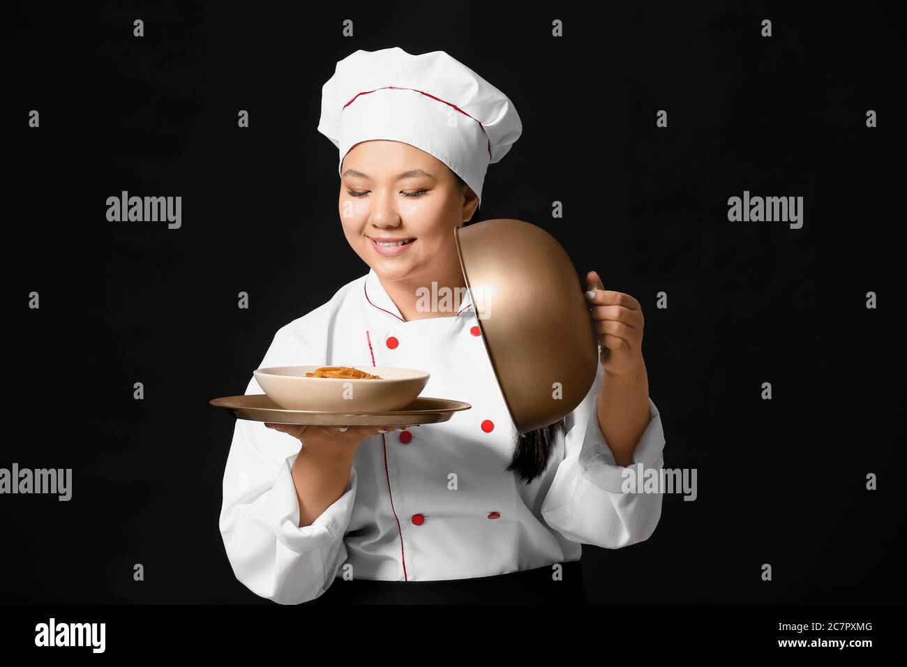 Beautiful Asian chef with dish on dark background Stock Photo - Alamy