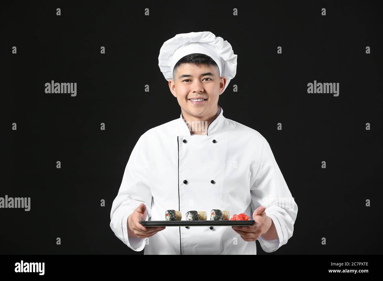 Handsome Asian chef with sushi rolls on dark background Stock Photo - Alamy
