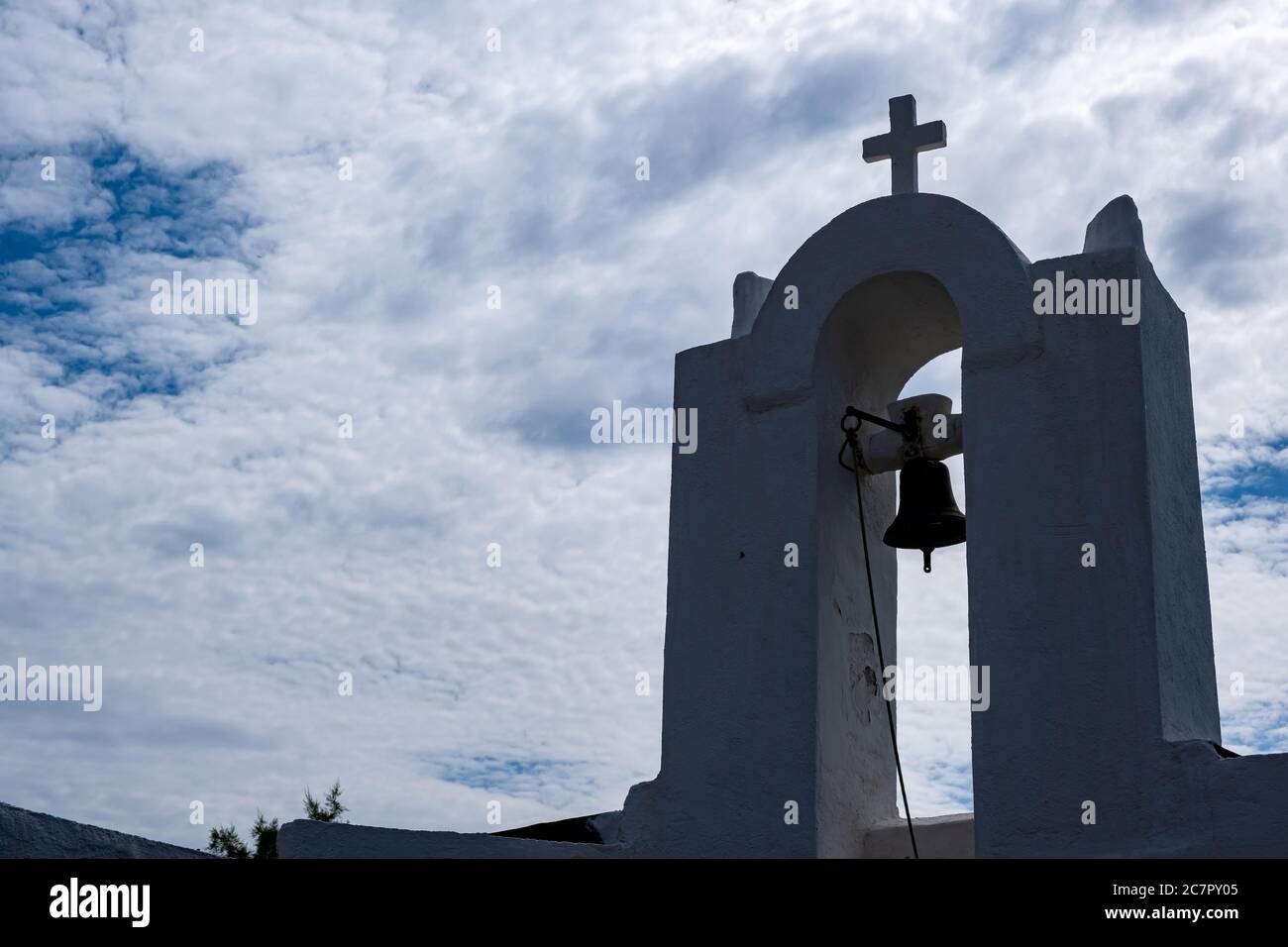 Small church belfry detail, whitewashed, mountains and blue cloudy sky ...