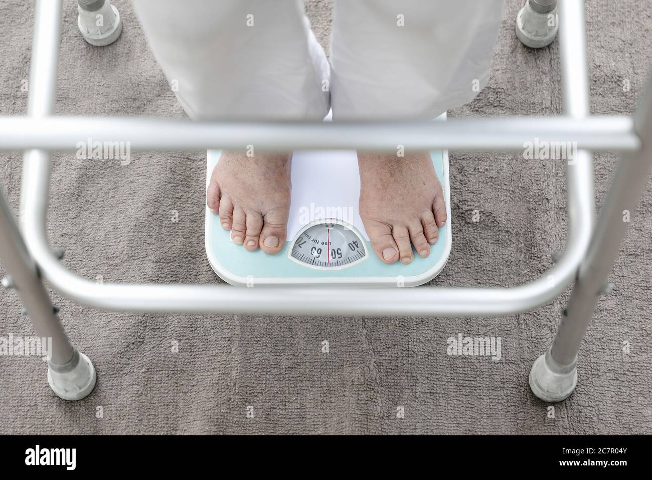 Eldely female standing on weight scale , her weight measure 54 kg Stock ...