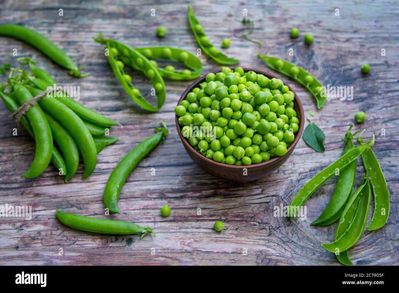 Fresh green peas in a bowl and pods on a rustic wooden table Stock ...