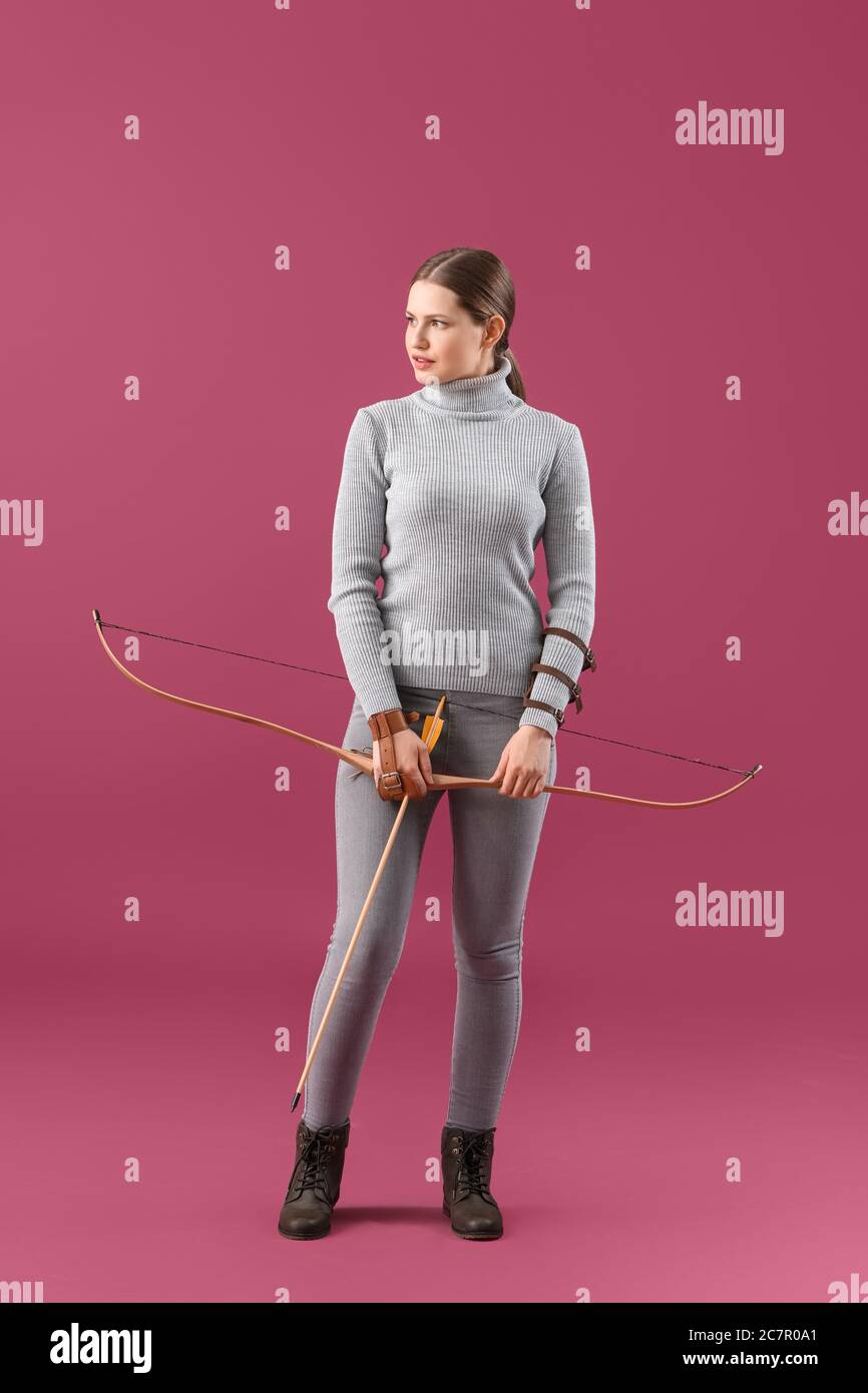 Beautiful woman with crossbow on color background Stock Photo - Alamy