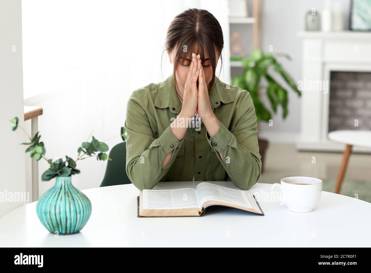 Young woman with Bible praying at home Stock Photo - Alamy