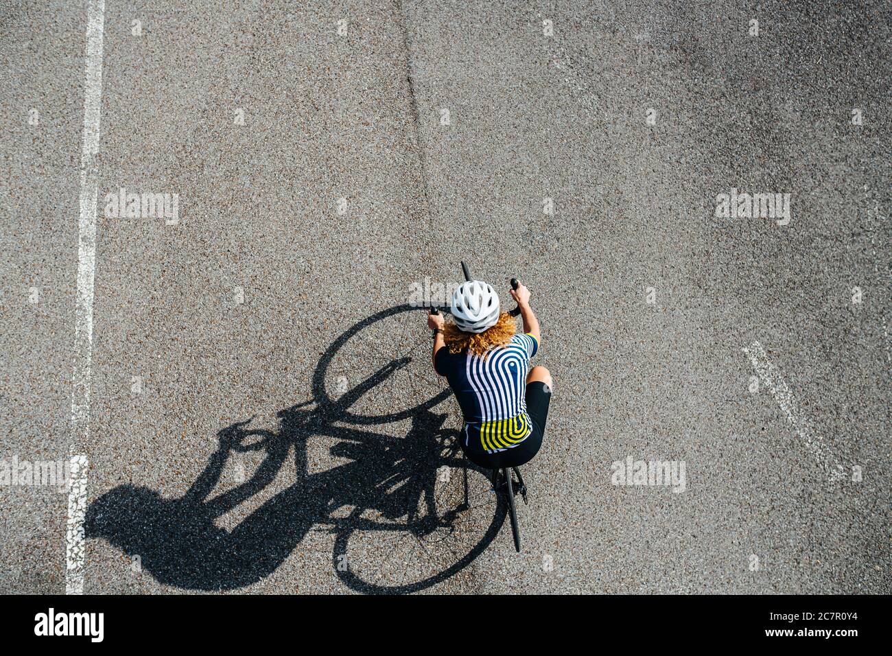 Woman cycling on a professional bike in a white helmet, shot from above ...