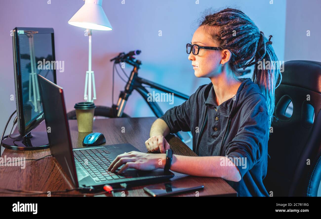 Modern young female programmer is writing program code on a laptop at ...