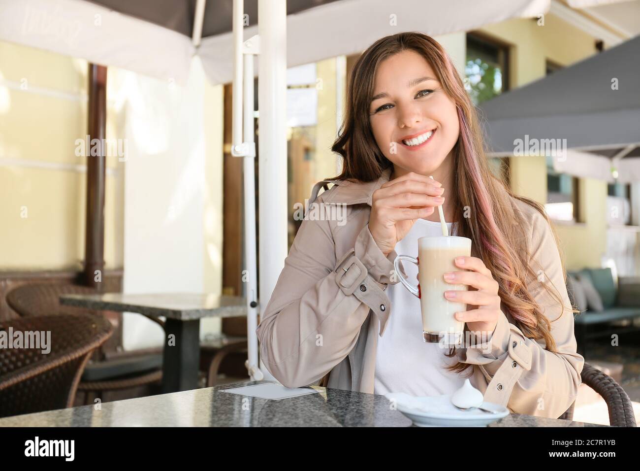 Young woman drinking hot coffee in outdoor cafe Stock Photo - Alamy