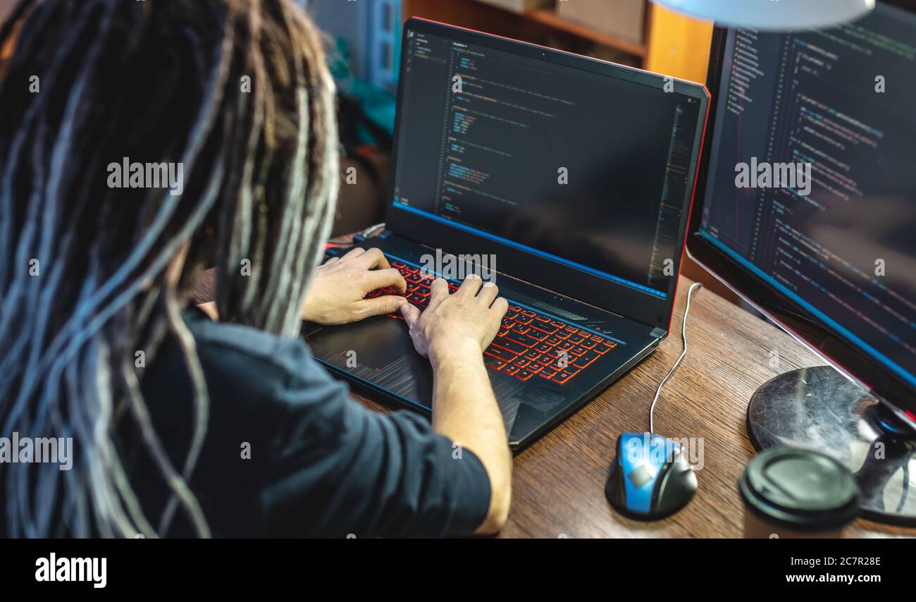 Modern young female programmer is writing program code on a laptop at ...