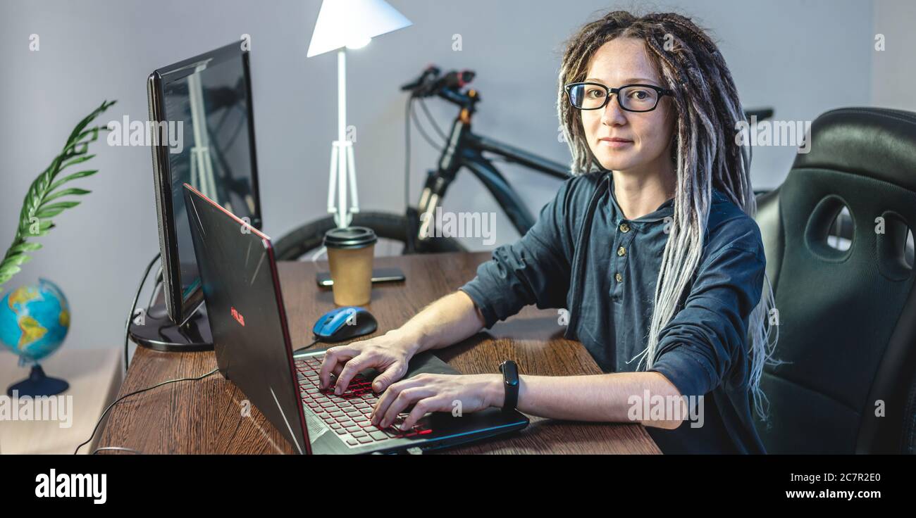 Modern young female programmer is writing program code on a laptop at ...