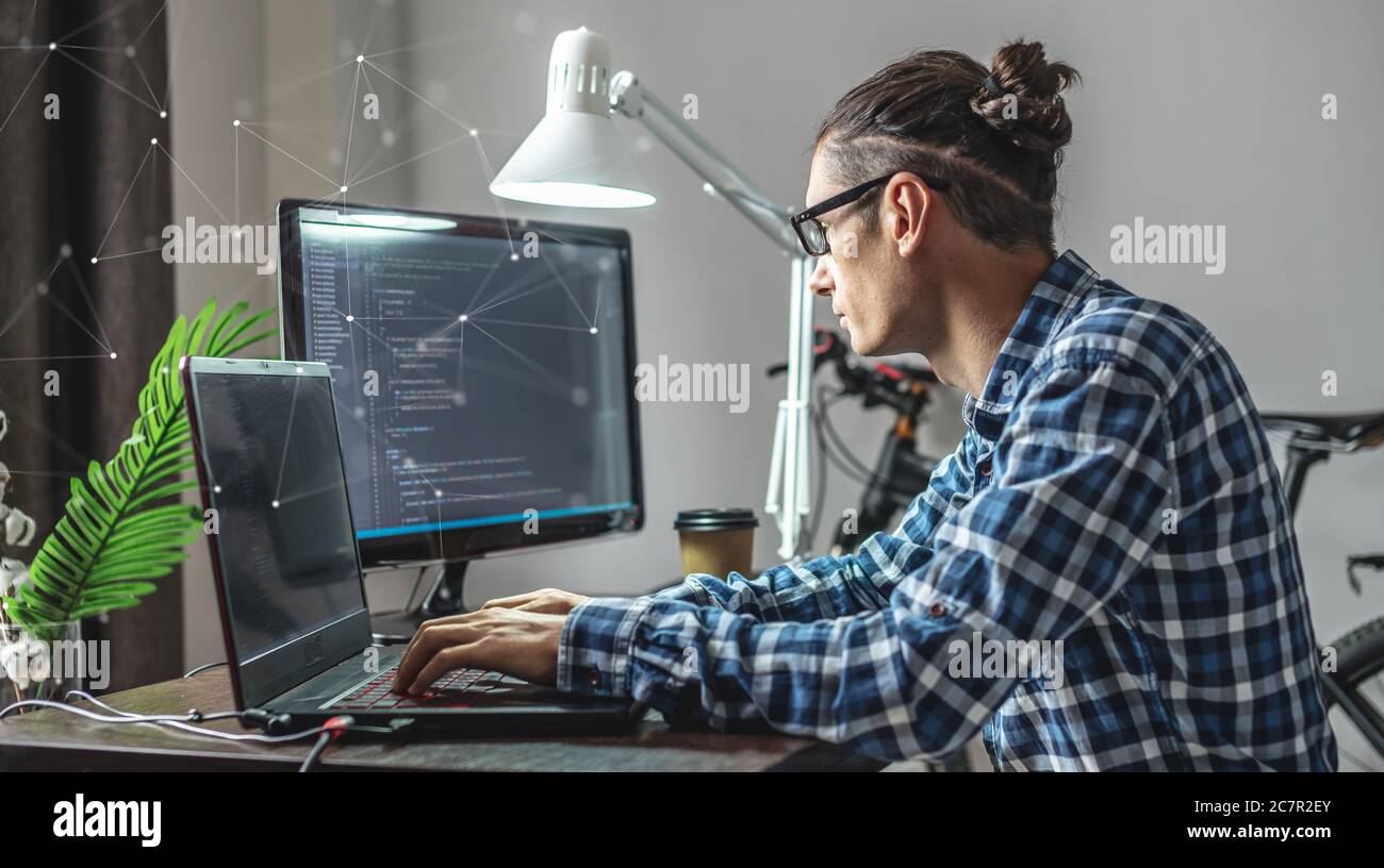 Male programmer is writing program code on a laptop at home. Remote ...