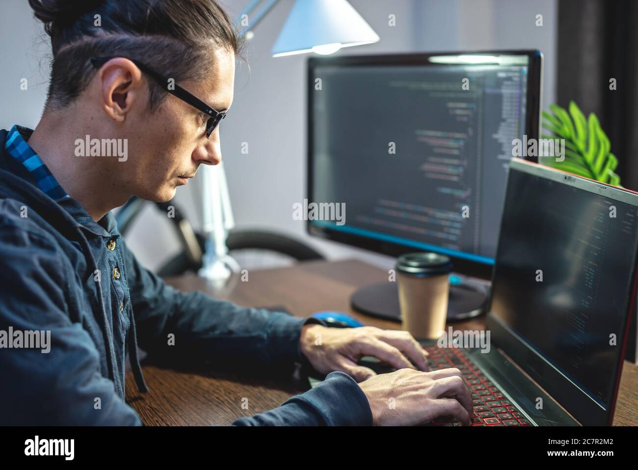 Male programmer is writing program code on a laptop at home. Remote ...