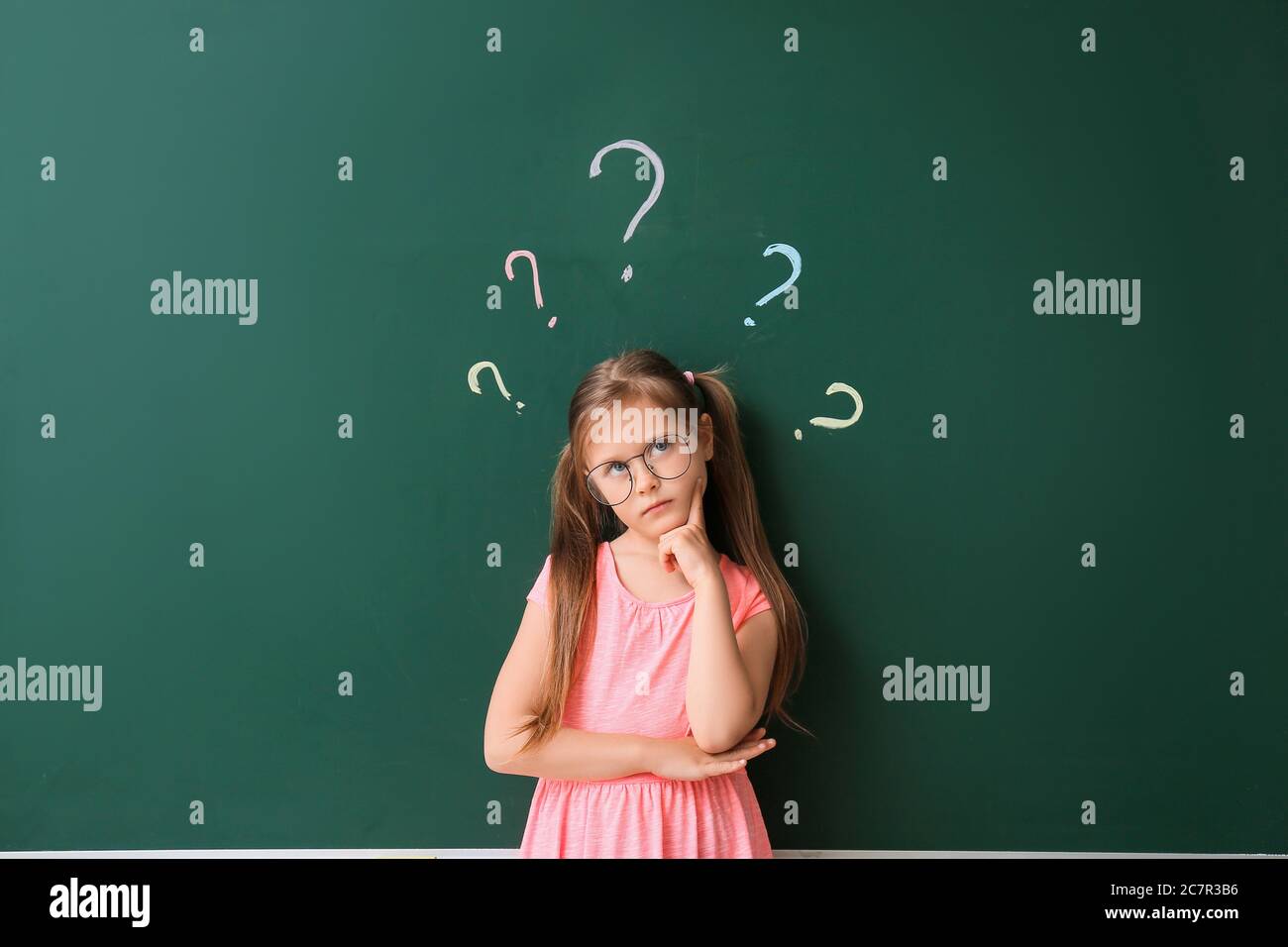 Thoughtful little schoolgirl near blackboard in classroom Stock Photo ...