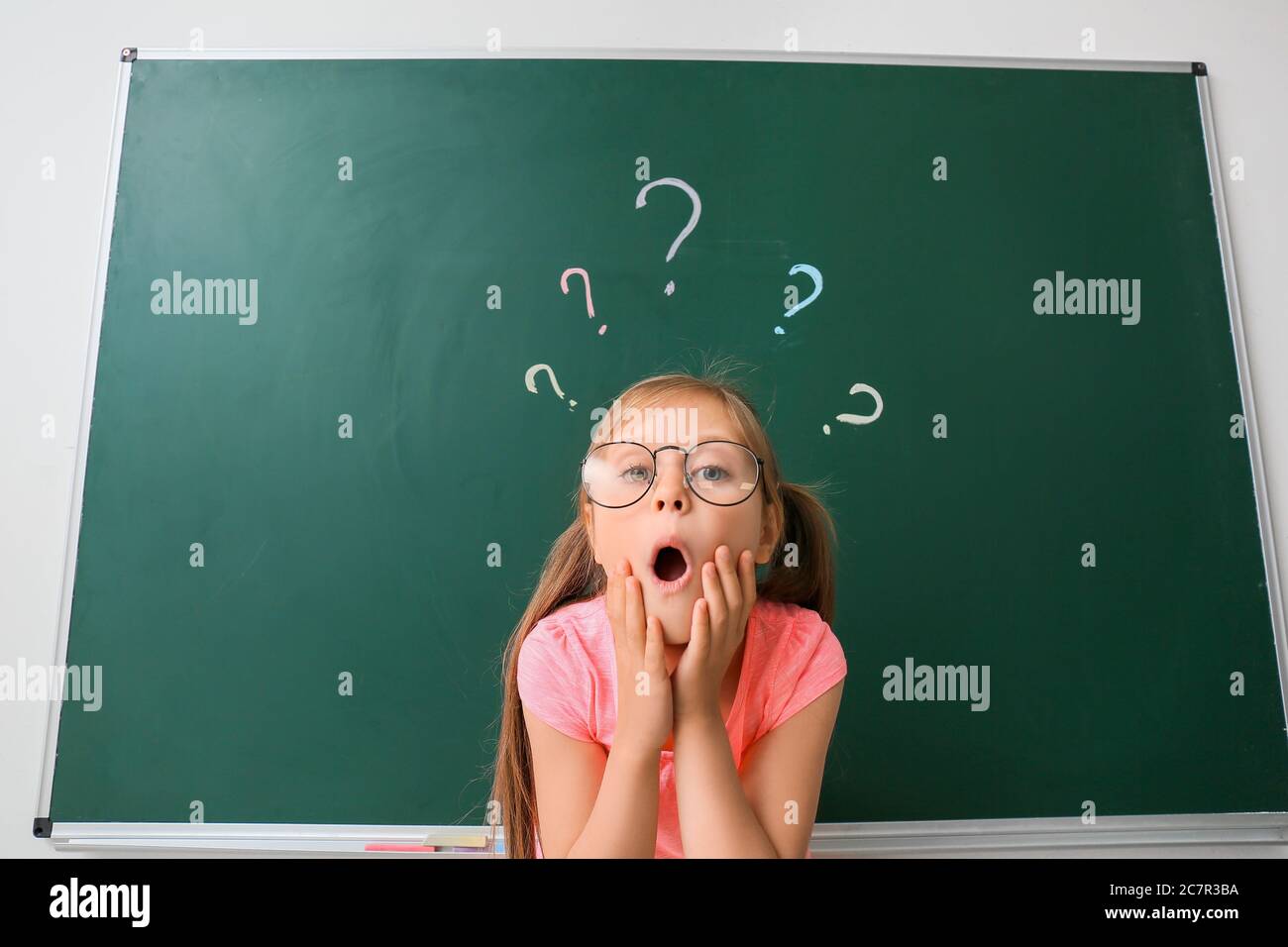 Shocked little schoolgirl near blackboard in classroom Stock Photo - Alamy