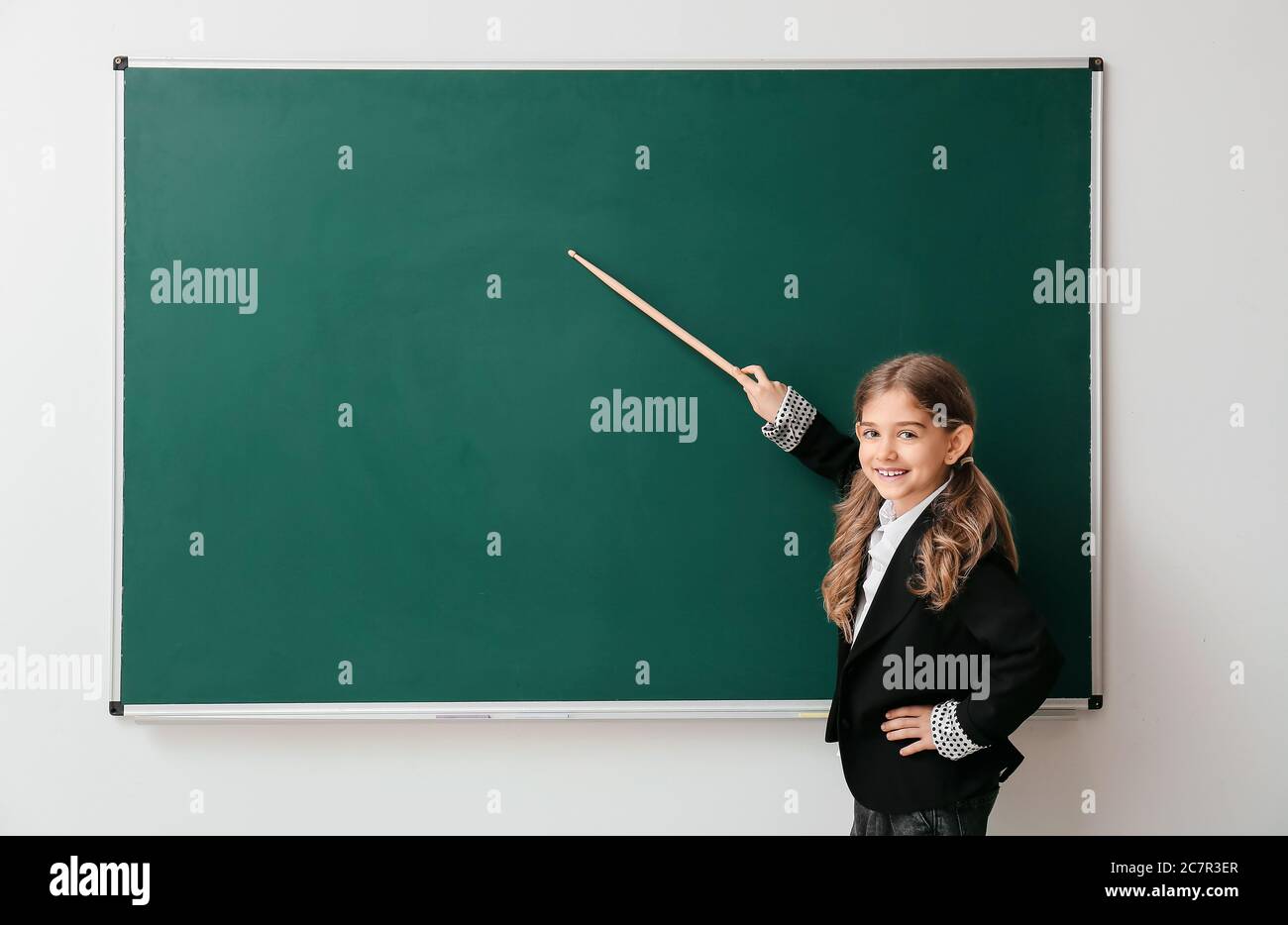 Cute little schoolgirl with pointer near blackboard in classroom Stock ...