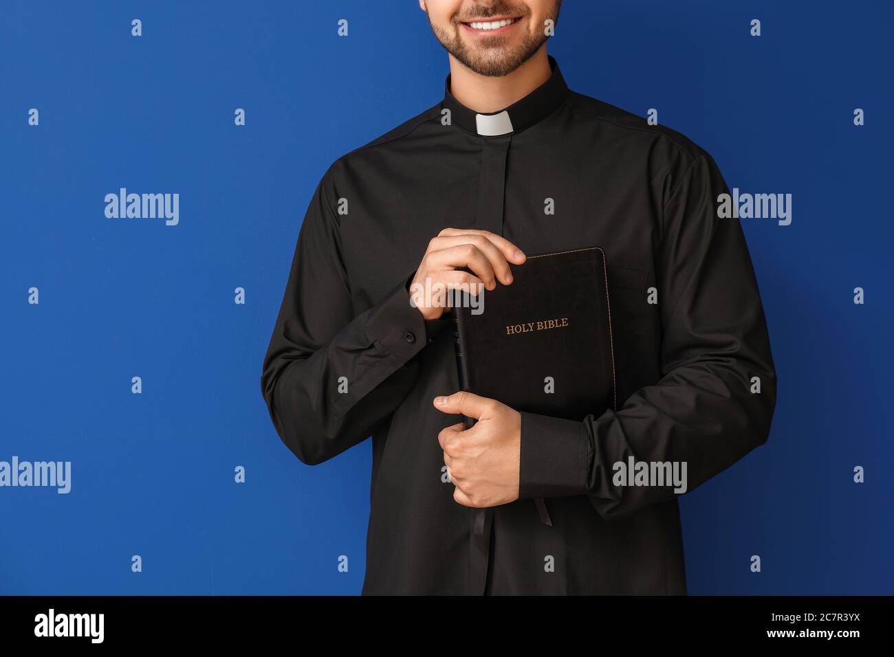 Young priest with Bible on color background Stock Photo - Alamy