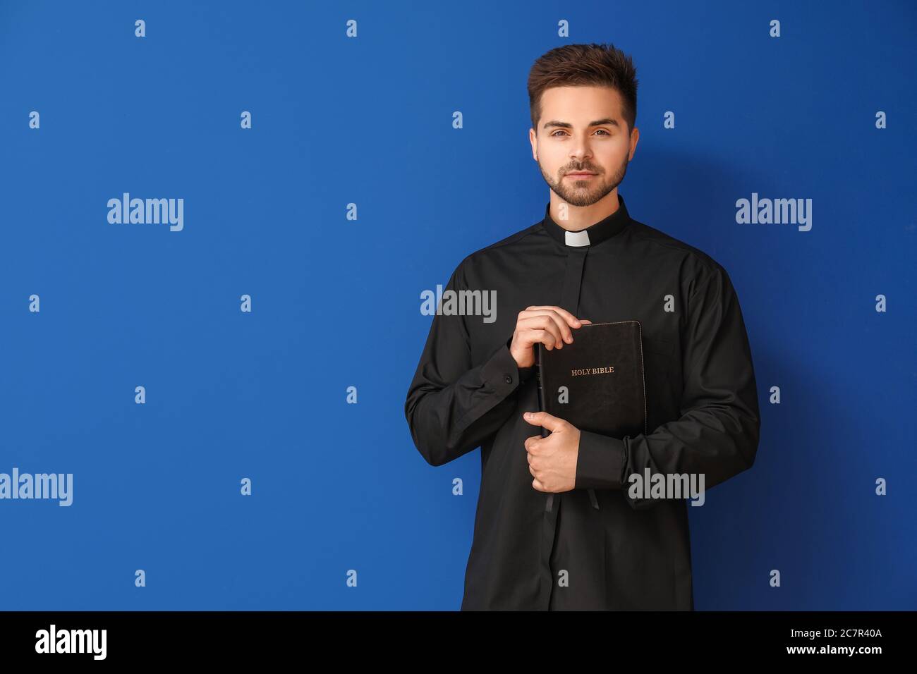 Young priest with Bible on color background Stock Photo - Alamy