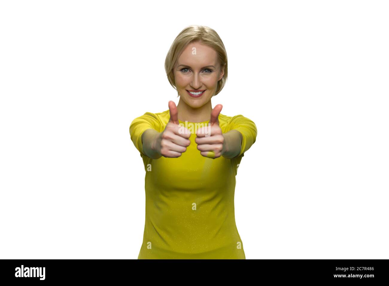 Happy woman in yellow showing okay with both hands on white background ...