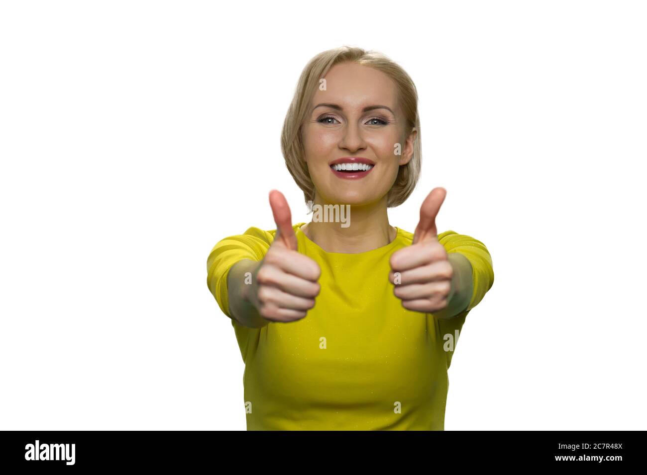 Smiling girl making thumbs up sign with both hands on white background ...