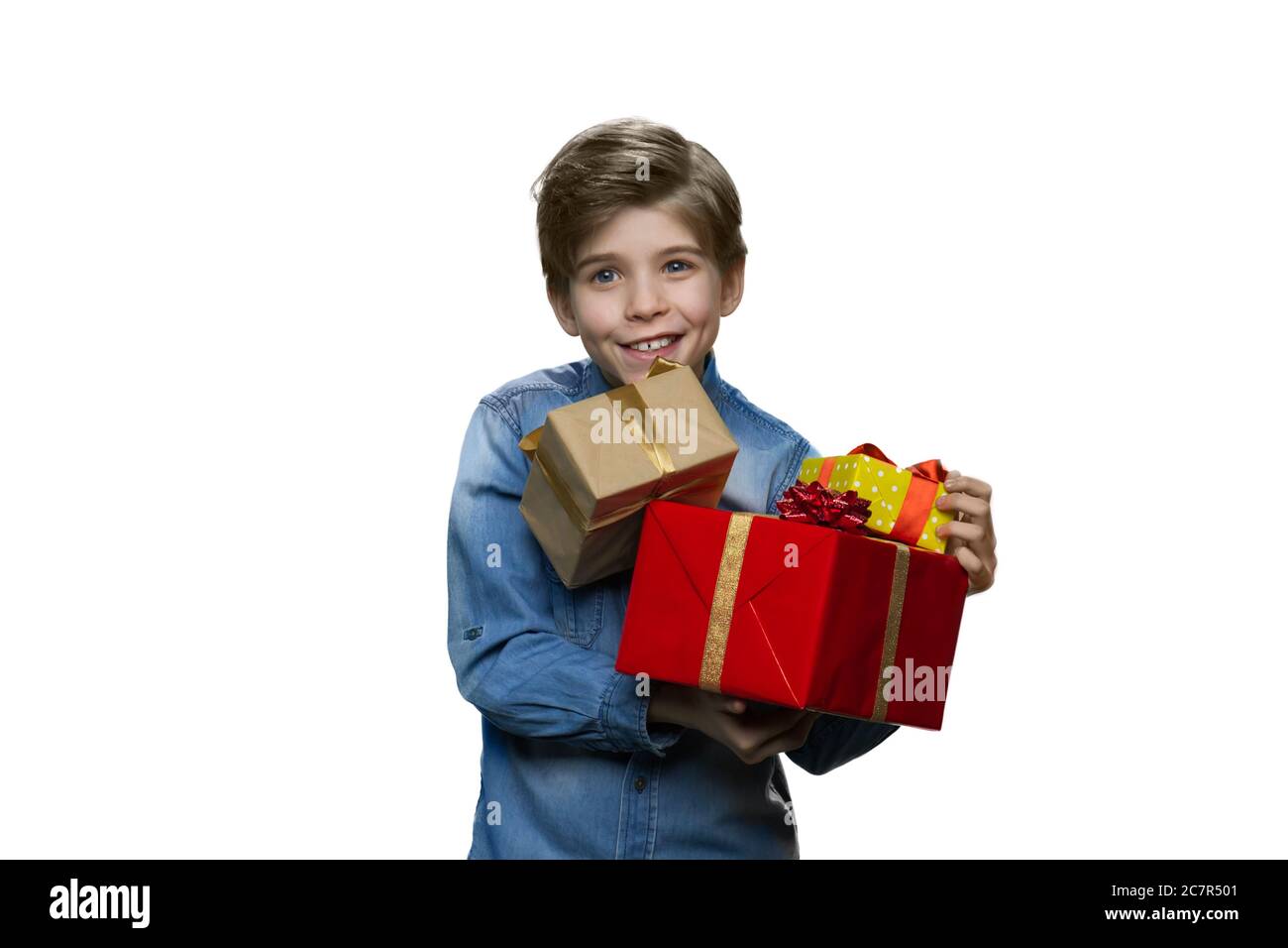 Teenage boy in denim clothes holding lots of present boxes on white ...