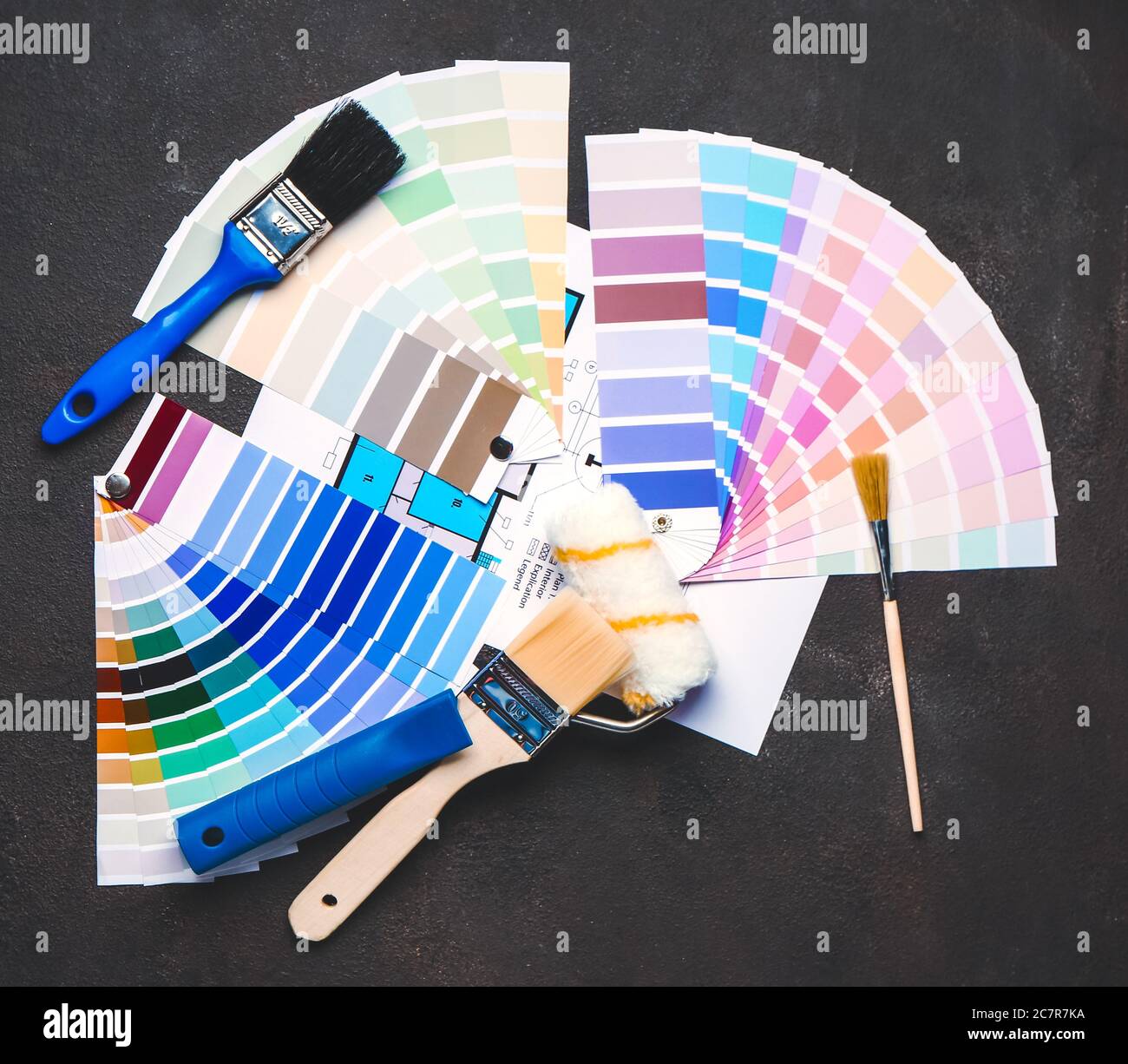 Color palettes with building plan, roller and paint brushes on dark ...