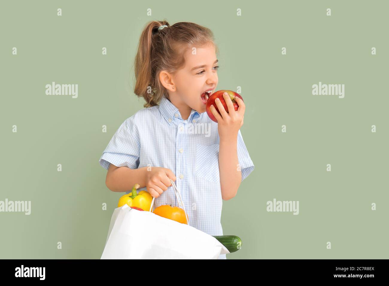 Little girl with food in bag on color background Stock Photo - Alamy
