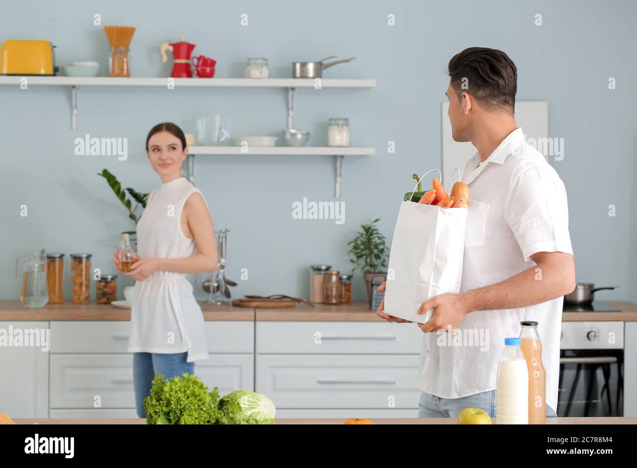 Couple unpacking fresh products from market in kitchen Stock Photo - Alamy