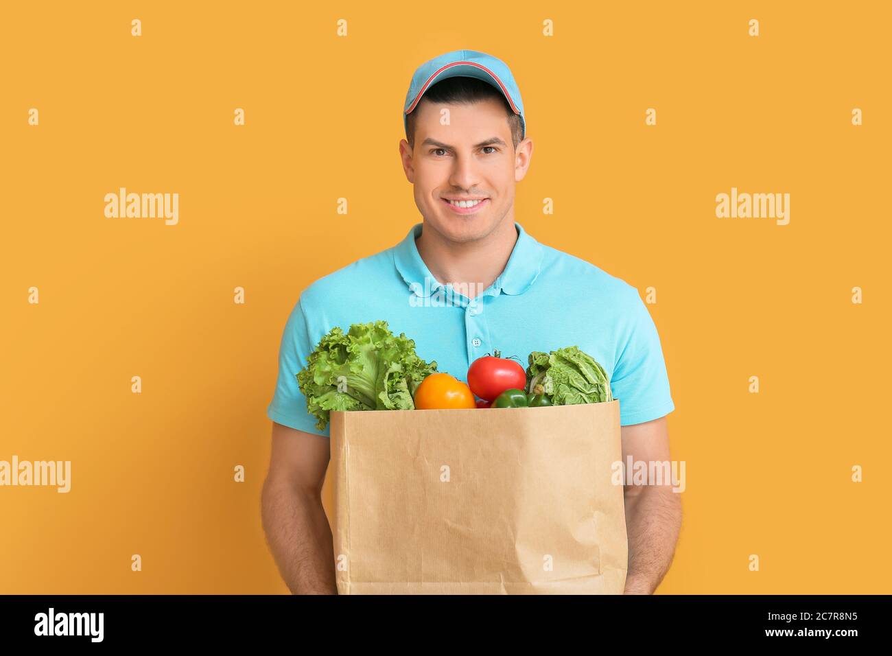 Delivery man with food in bag on color background Stock Photo - Alamy