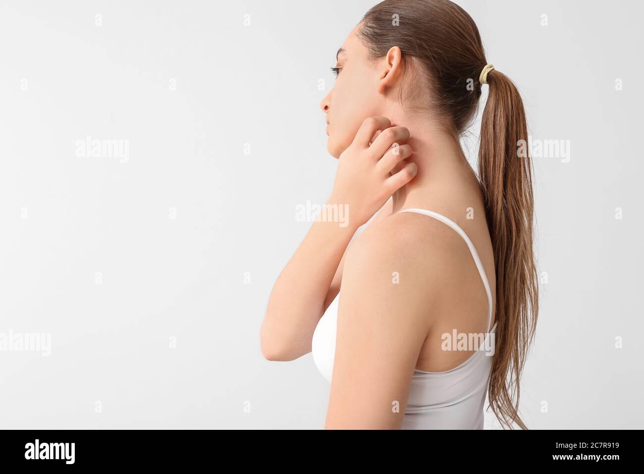Young woman scratching her skin on light background Stock Photo - Alamy