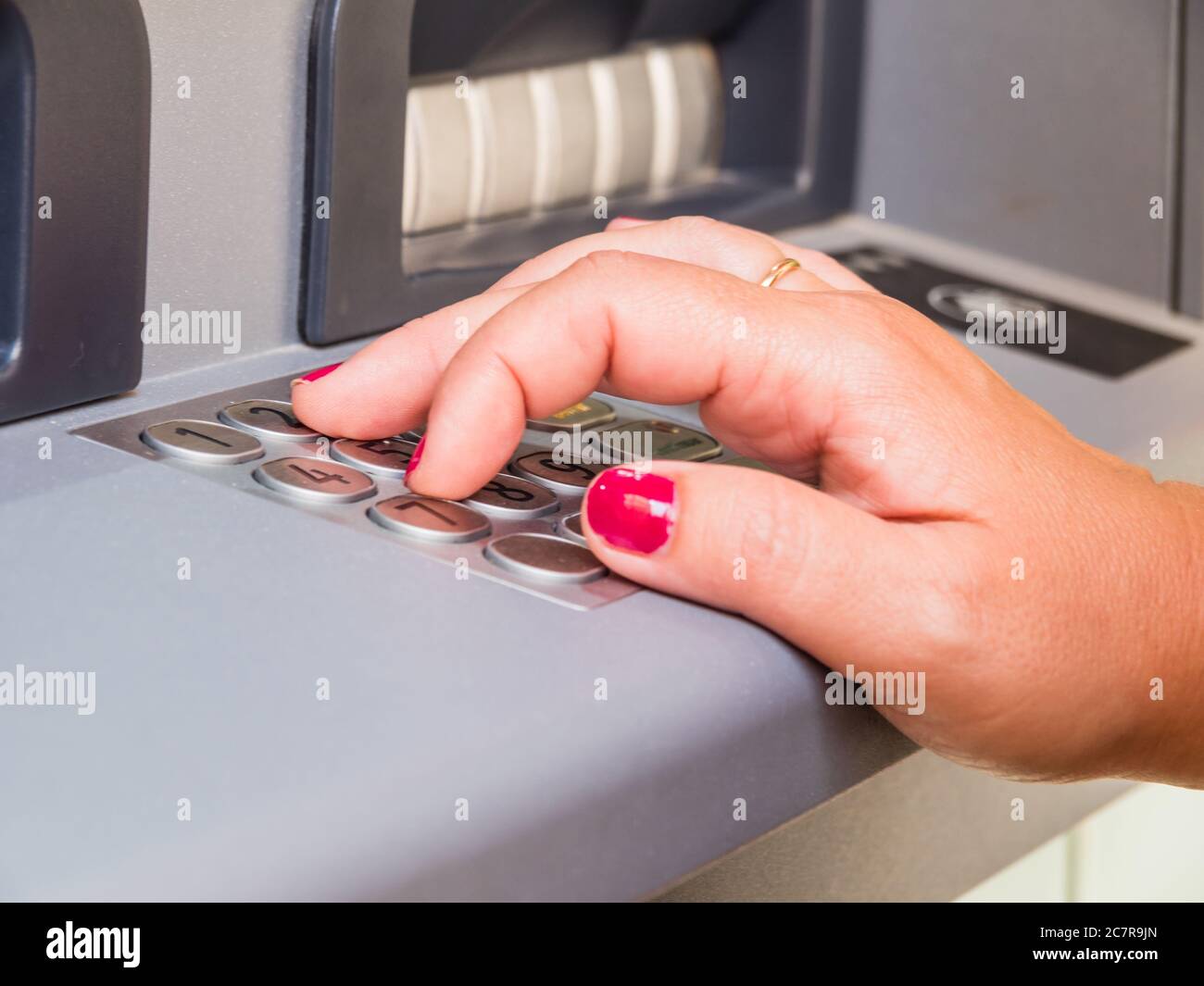 Closeup shot of a female hand pressing buttons on an ATM machine keypad ...
