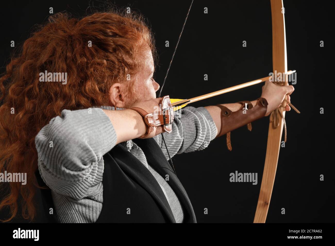 Beautiful female archer with bow on dark background Stock Photo - Alamy