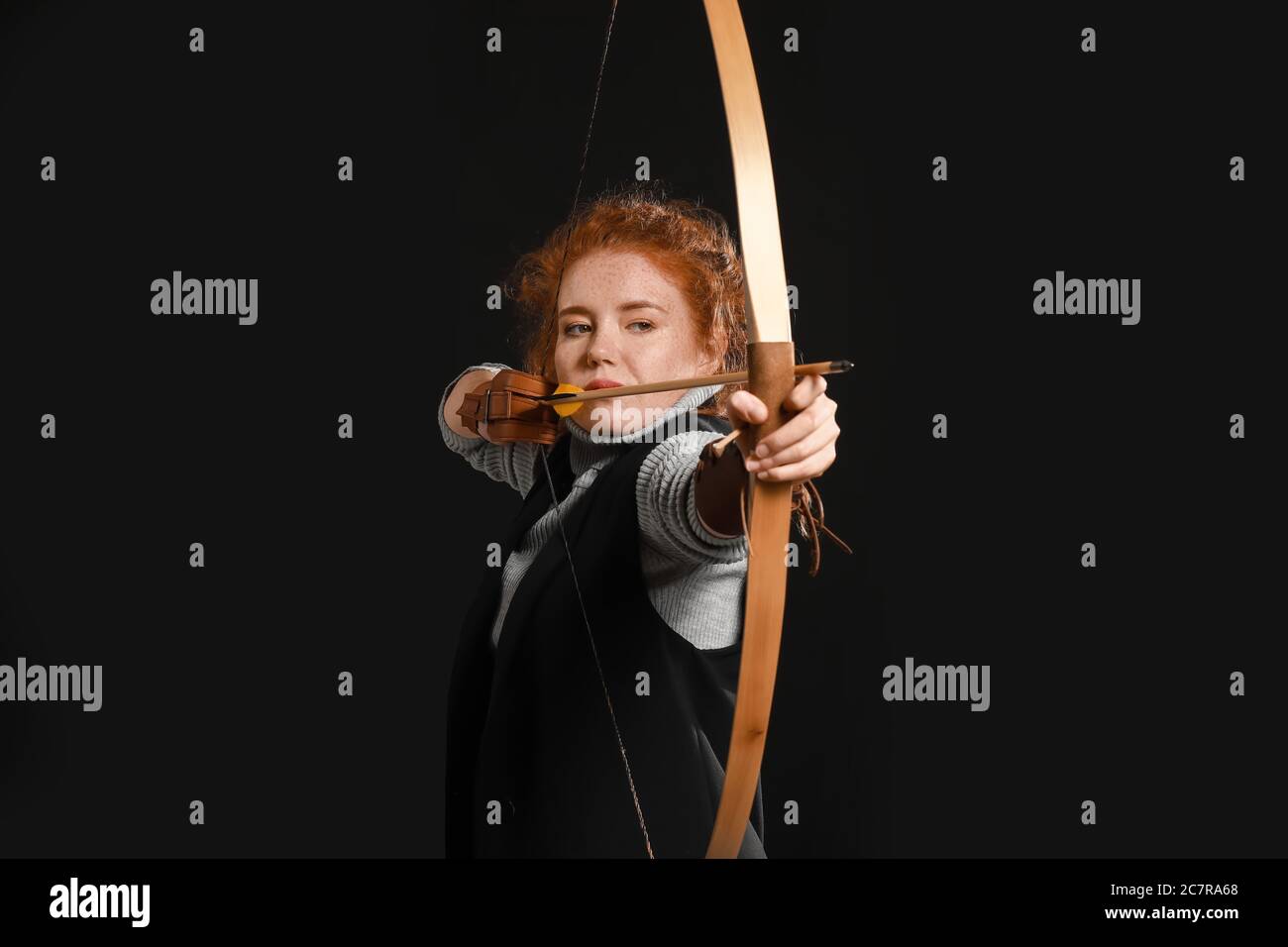 Beautiful female archer with bow on dark background Stock Photo - Alamy