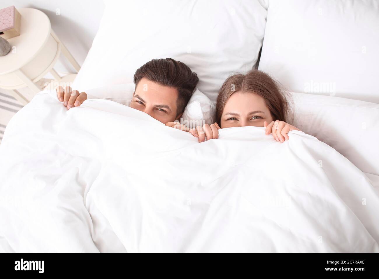 Morning of happy young couple lying in bed Stock Photo - Alamy