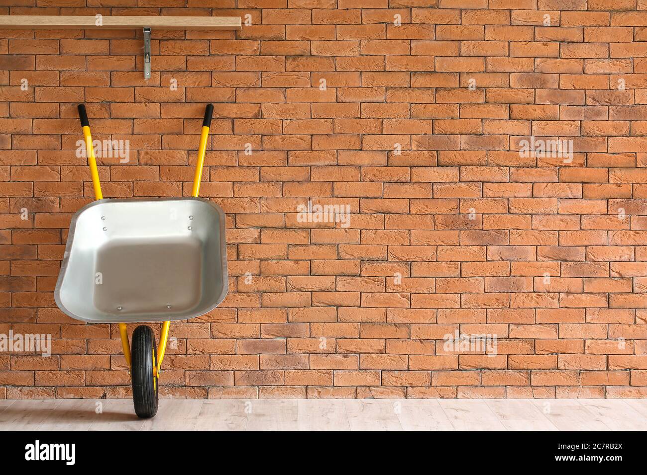 Empty wheelbarrow near brick wall Stock Photo - Alamy