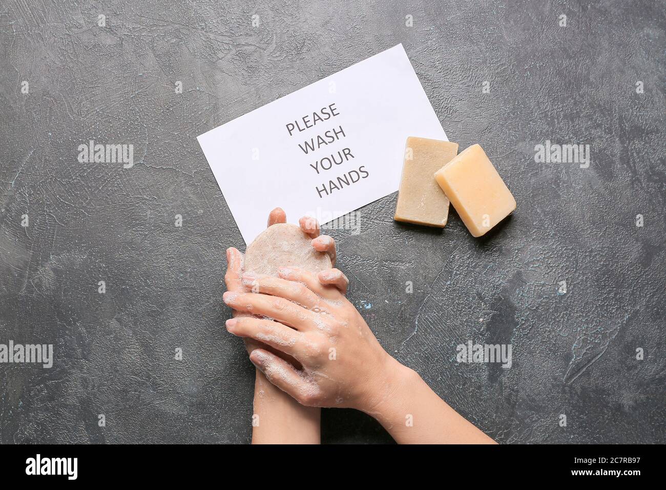 Female hands holding soap and paper with text PLEASE, WASH YOUR HANDS ...