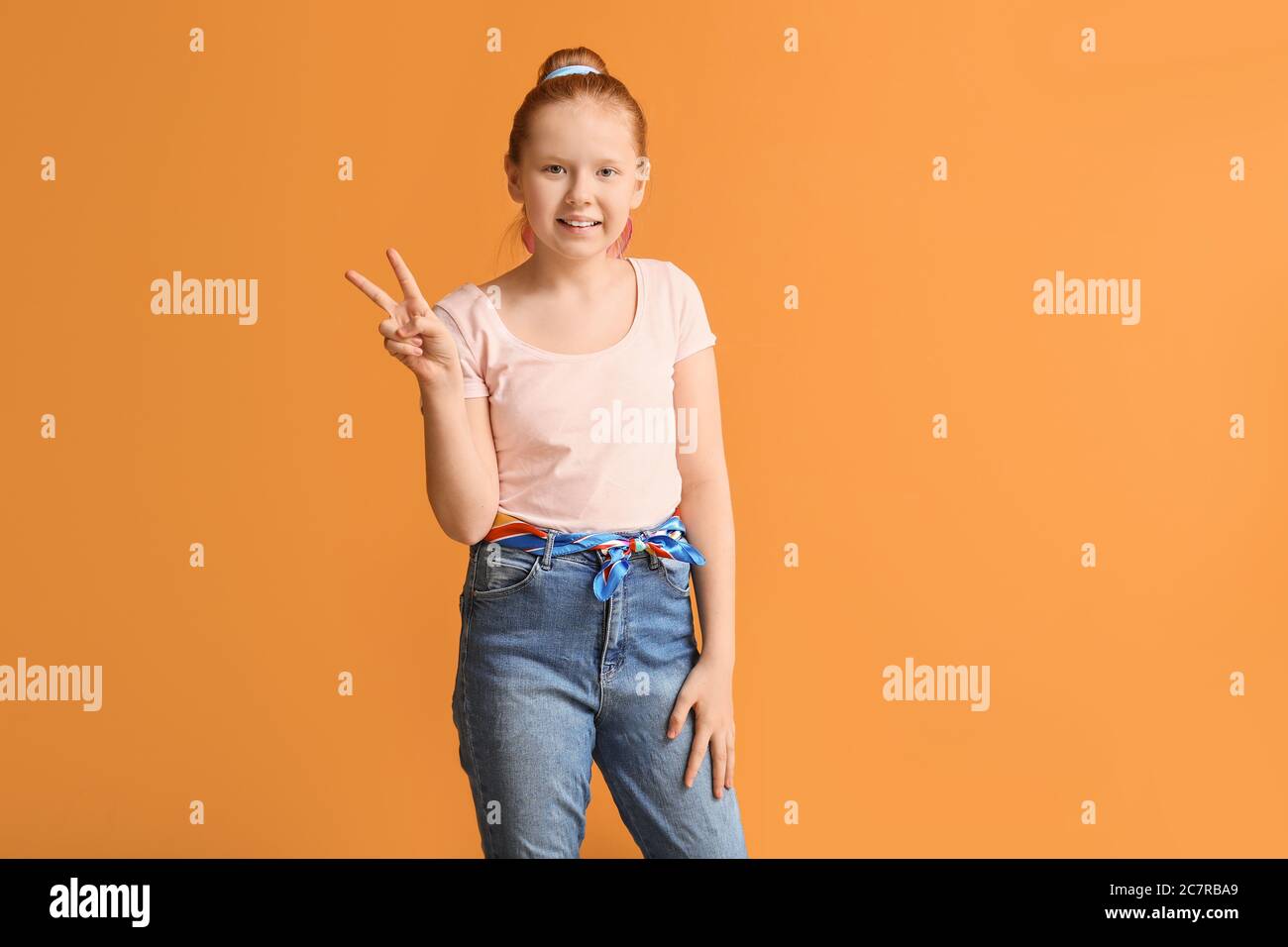 Cute redhead girl showing victory gesture on color background Stock ...