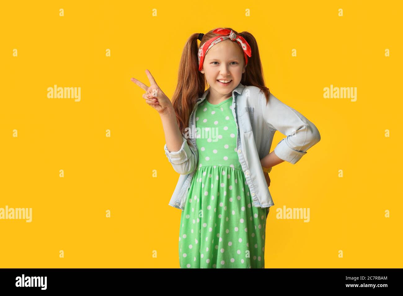 Cute redhead girl showing victory gesture on color background Stock ...