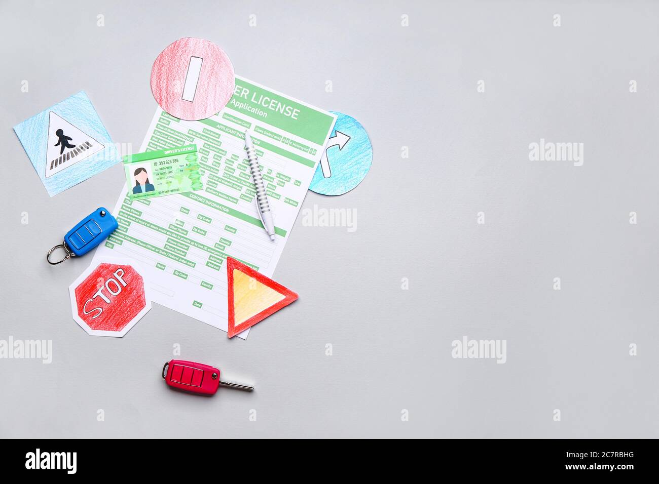 Driving license with application form, car keys and road signs on grey ...