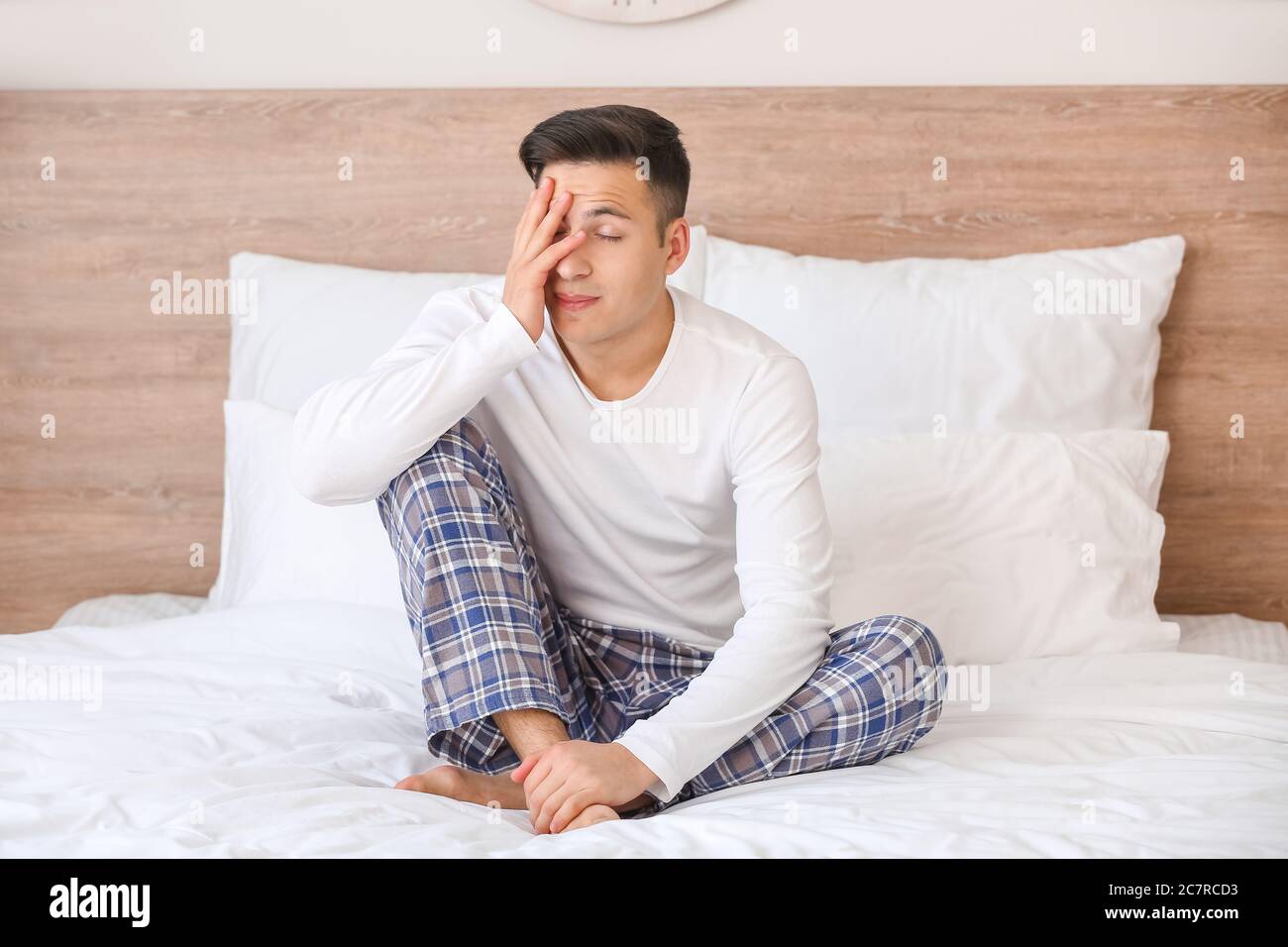 Young man suffering from sleep deprivation in bedroom Stock Photo - Alamy