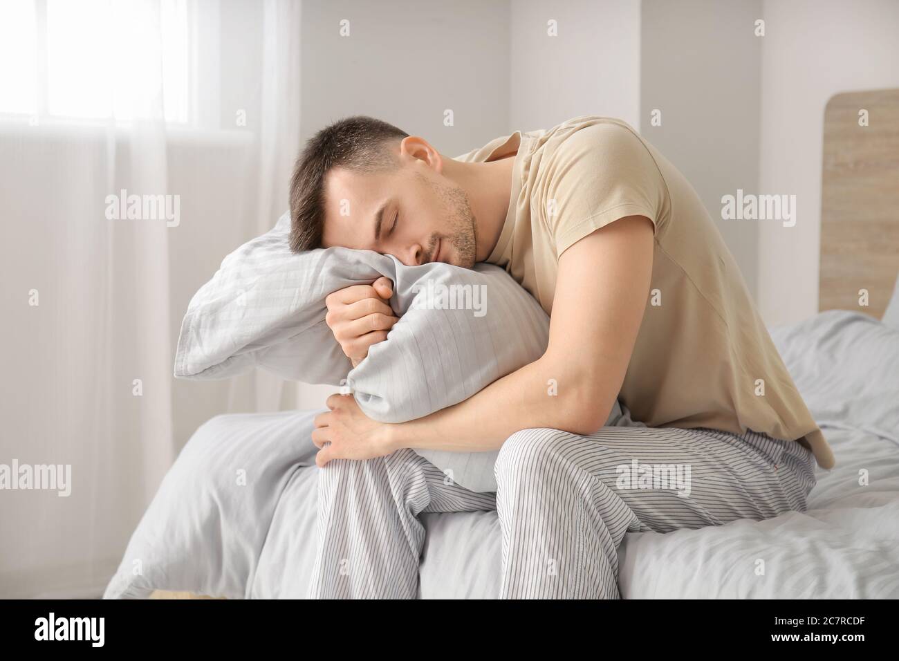 Young man suffering from sleep deprivation in bedroom Stock Photo - Alamy