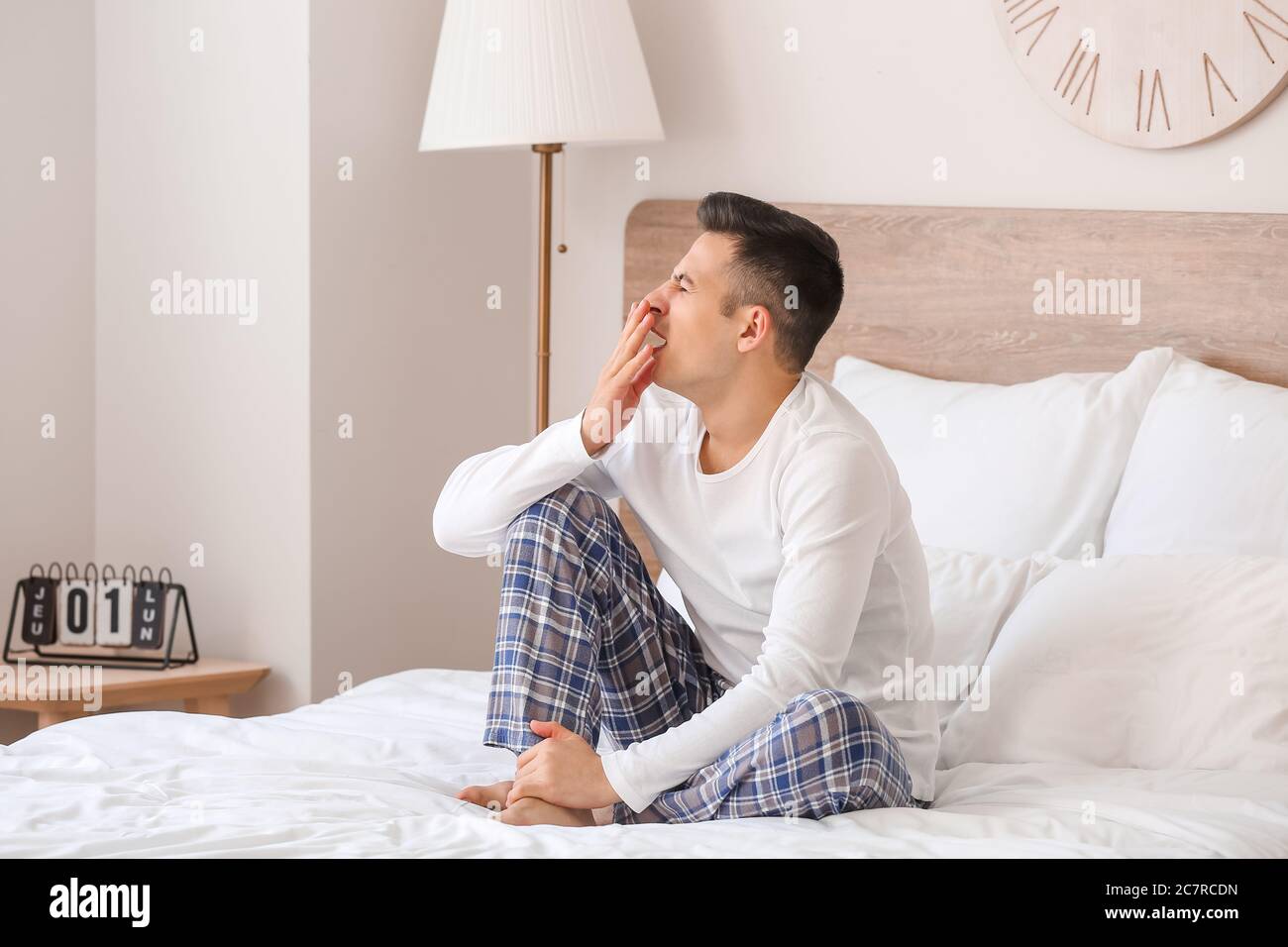 Young man suffering from sleep deprivation in bedroom Stock Photo - Alamy