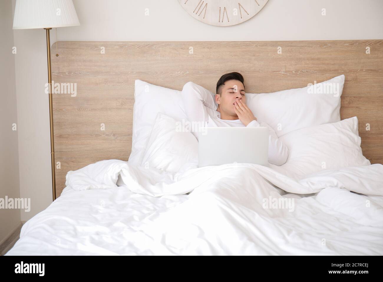 Young man suffering from sleep deprivation with laptop in bedroom Stock ...